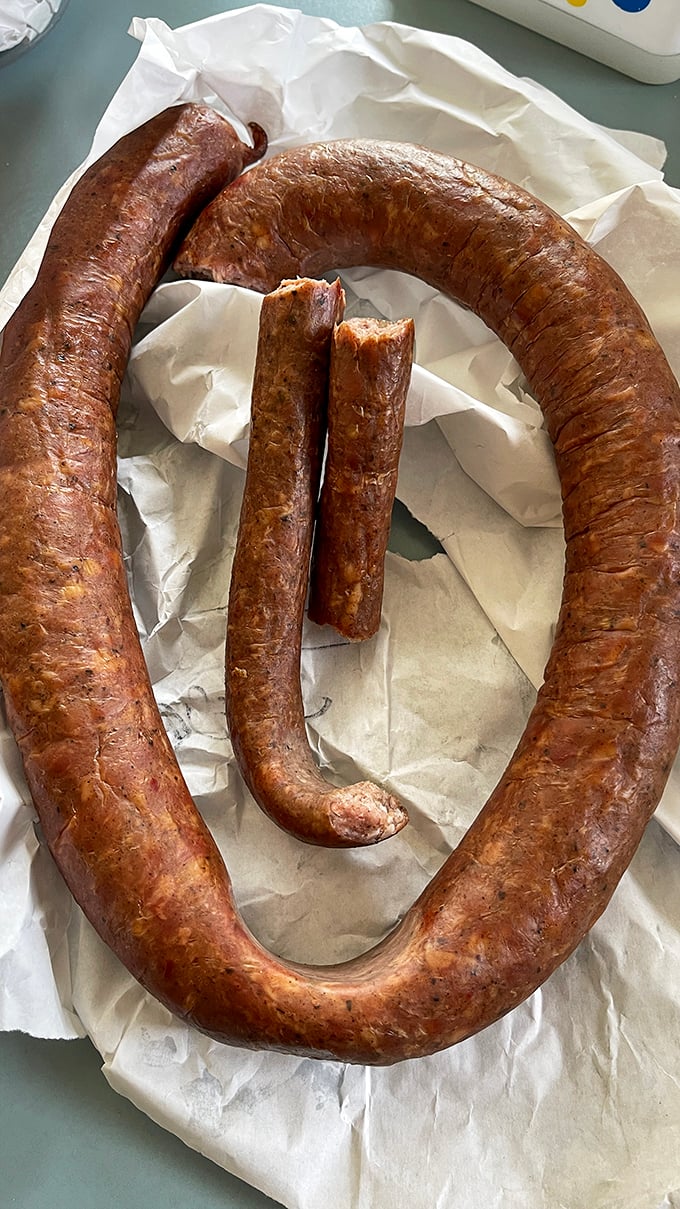 The kielbasa loop—nature's most perfect circle. Smoke-kissed, glistening, and ready to make your sandwich dreams come true. 