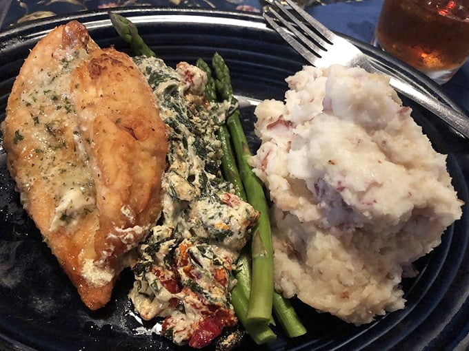 This isn't just chicken—it's a masterclass in comfort. Spinach-stuffed breast alongside creamy mashed potatoes and asparagus spears standing at attention.