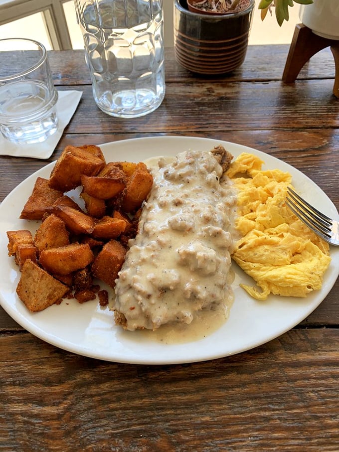 Biscuits and gravy that could settle regional disputes—creamy, peppery gravy cascading over golden home fries and fluffy scrambled eggs.