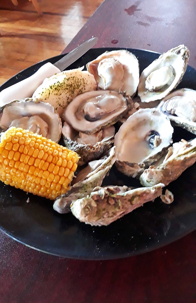 Plump, glistening oysters served with a side of corn—proof that sometimes the simplest presentations let truly fresh seafood shine brightest.