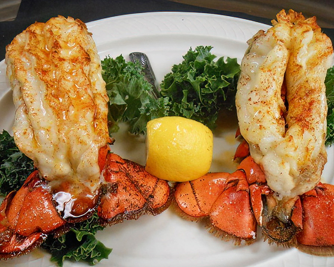 Twin lobster tails perched like royalty on a bed of greens – Neptune himself would approve of this oceanic treasure.
