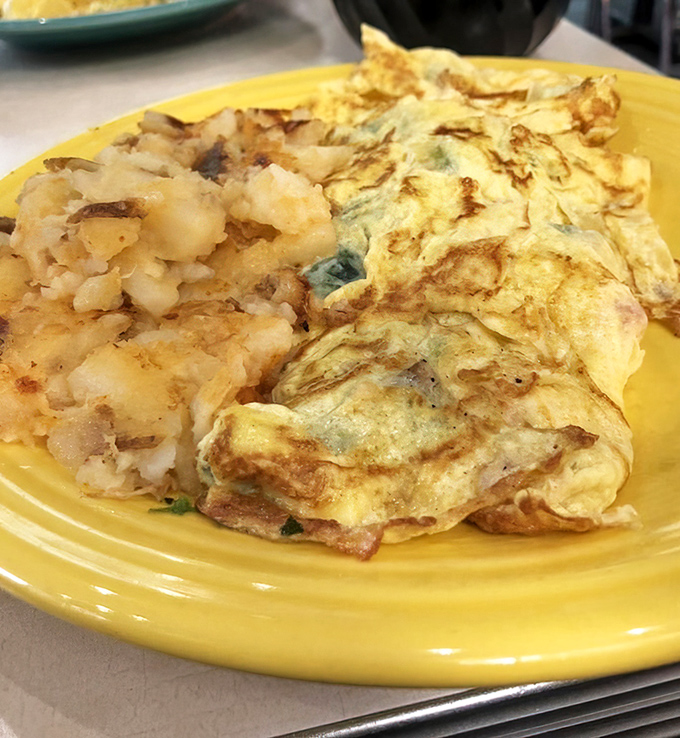The perfect omelet doesn't exi—oh wait, here it is! Fluffy egg perfection alongside those legendary lyonnaise potatoes that steal the show.