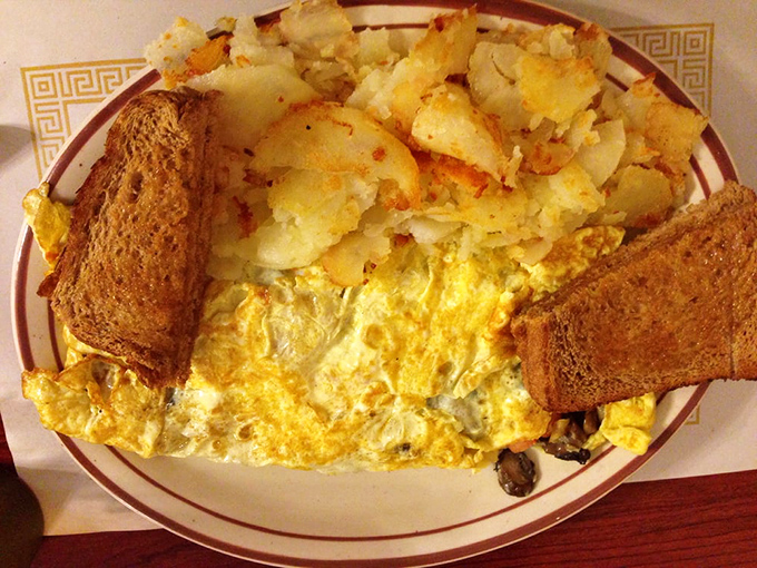 This isn't just an omelet—it's a golden canvas of eggs cradling melted cheese with home fries that could make a potato farmer weep with joy.