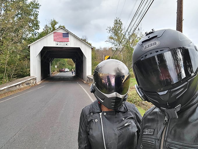 Two motorcycle enthusiasts pause for a moment of covered bridge appreciation—proving these historic structures draw admirers from every corner of the travel community.