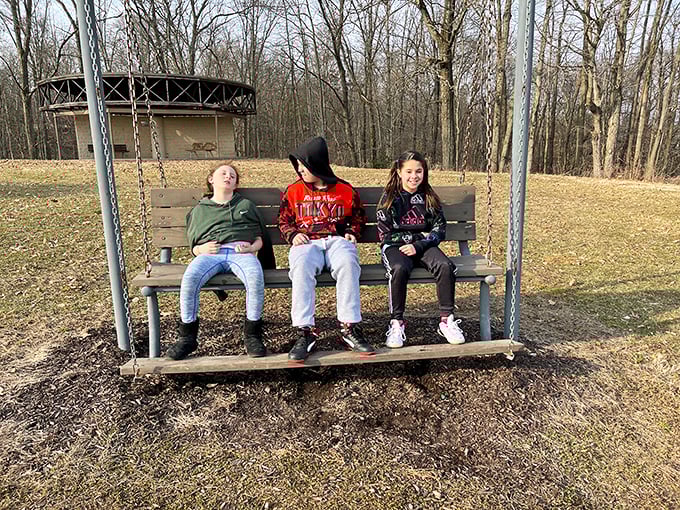 The simple joy of a park bench swing – where conversations flow, memories are made, and kids pretend they're not having fun with their parents.