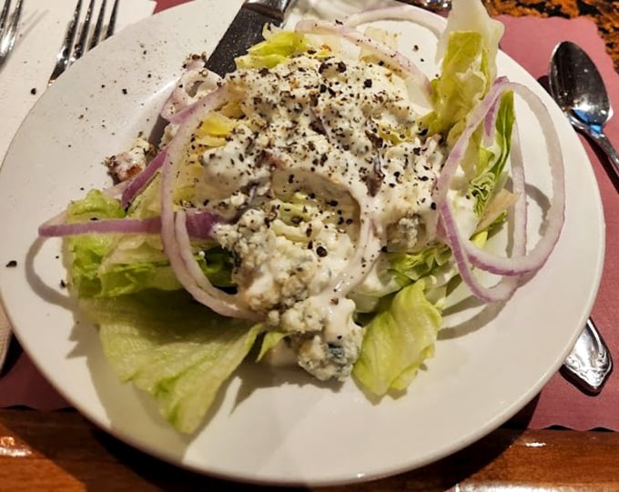 A wedge salad that means business—crisp iceberg lettuce, red onion rings, and blue cheese crumbles. The perfect opening act before the meaty main event.