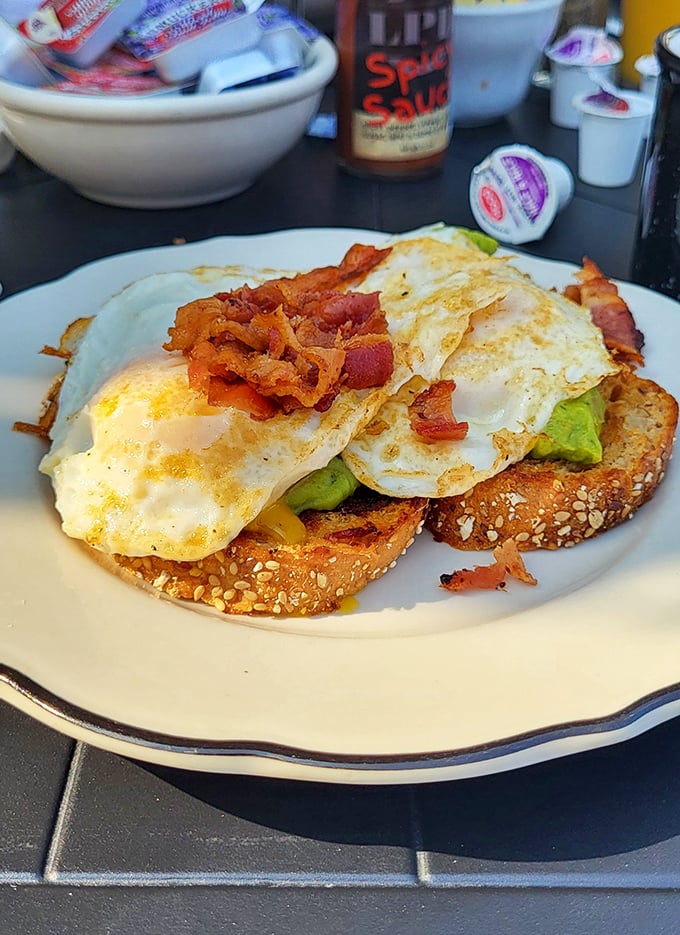 Avocado toast gets the diner treatment. Crispy bacon, perfectly fried eggs, and creamy avocado on seeded bread—proof that classics can embrace modern favorites.