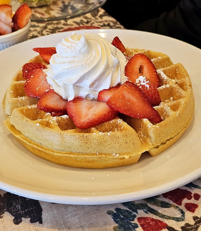 A Belgian waffle topped with fresh strawberries and whipped cream—proof that sometimes the classics don't need reinventing, just perfecting.