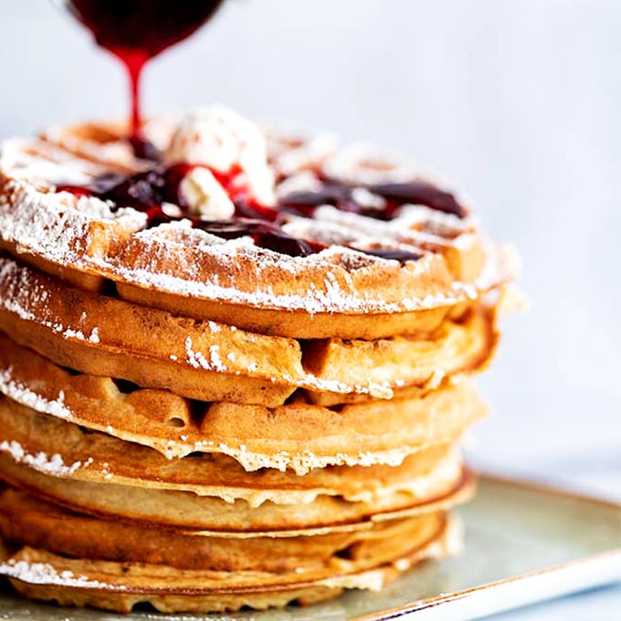 These Belgian waffles aren't just breakfast, they're architecture – golden, crispy foundations supporting a sweet berry masterpiece that demands attention.
