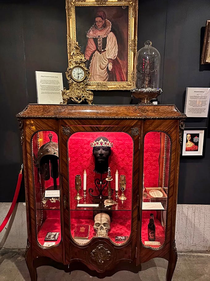 Victorian elegance meets macabre fascination in this ornate display cabinet, where a crowned skull holds court among candles and antiques like a forgotten royal receiving visitors.