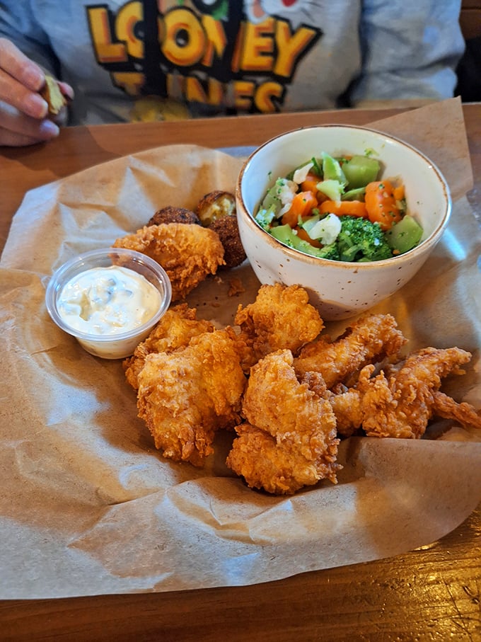 Golden-fried treasures nestled alongside vibrant vegetables—proof that sometimes the best things in life come in paper-lined baskets.