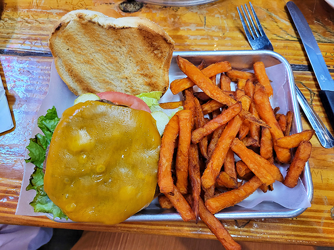 Behold the classic American cheeseburger in its natural habitat – juicy patty, melted cheese, and those sweet potato fries that somehow make you feel virtuous.