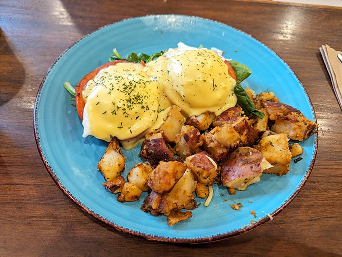 Eggs Benedict done right—golden hollandaise cascading down like a sunrise, with home fries that could make a potato farmer weep with pride.