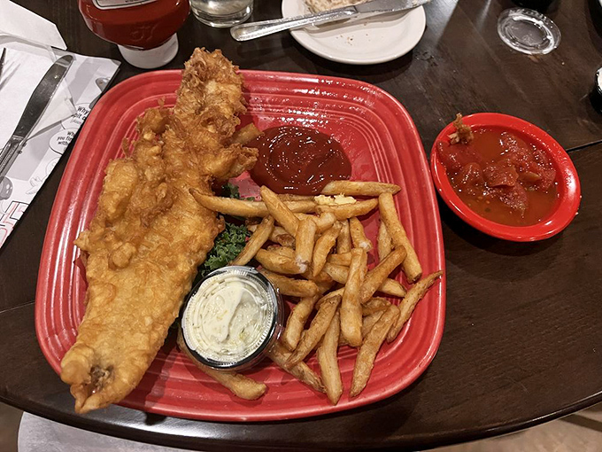 Fish and chips that would make a British pub proud, served on a festive red plate that says, "Yes, this is technically fried food, but it's the fancy kind."