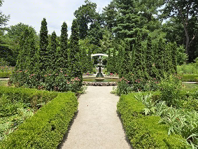 A classic fountain framed by perfectly manicured greenery. The formal garden offers a traditional counterpoint to the park's more avant-garde installations.