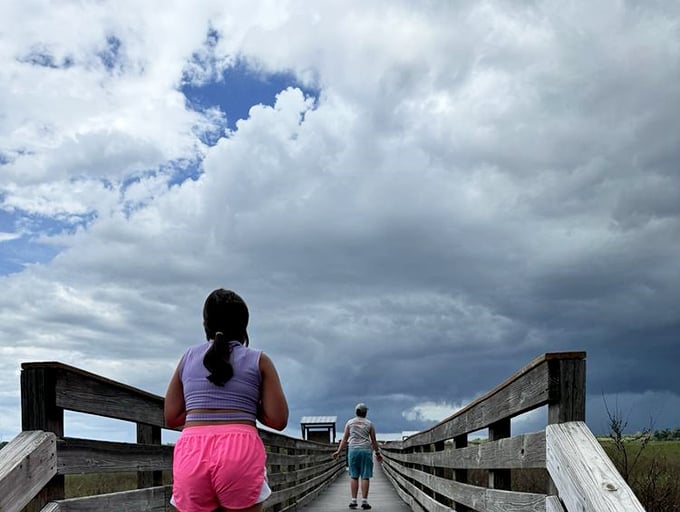 Storm clouds gather over the boardwalk, creating that dramatic lighting photographers chase and picnickers fear. Pure Florida theater.