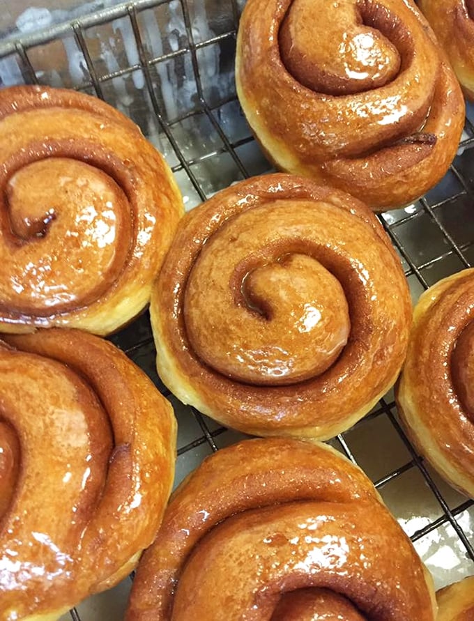 Fresh honeybuns await their chocolate baptism—the spiral design isn't just pretty, it creates perfect pockets where that sweet glaze can pool into flavor nirvana.