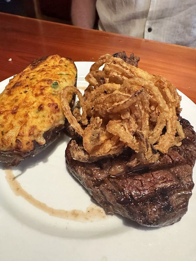 A steak topped with crispy onion strings and a stuffed potato—proof that sometimes the best relationships are the ones that sizzle.