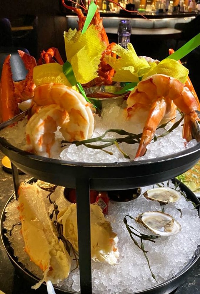 The seafood tower arrives like Neptune's personal offering – a multi-tiered monument to oceanic delights that demands reverent consumption.