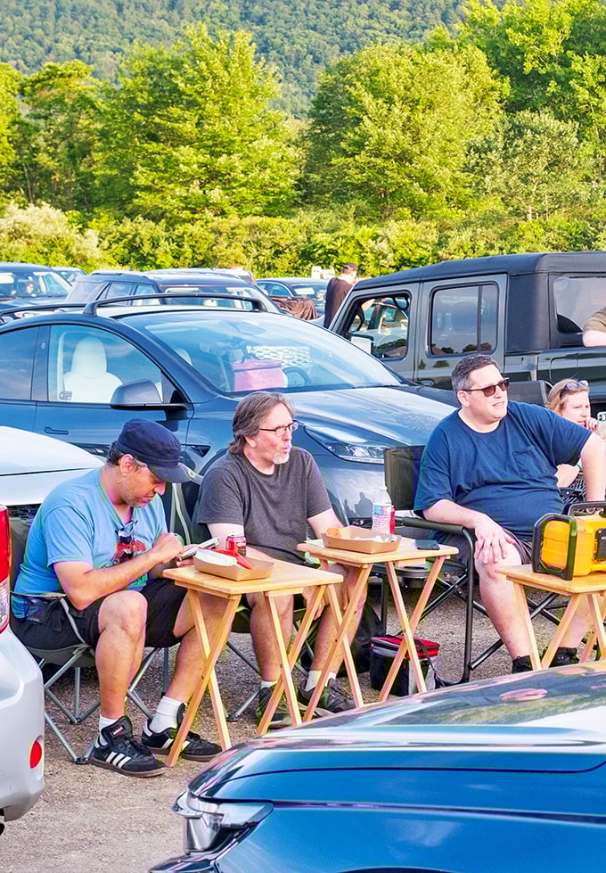 Film buffs gather between showings, swapping movie trivia while enjoying snacks from their perfectly positioned lawn chairs.