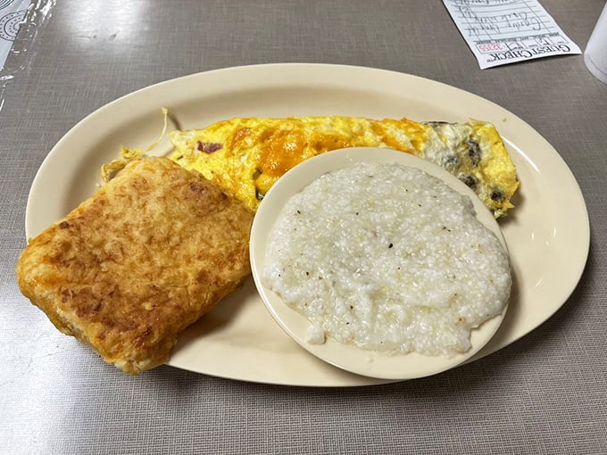 This isn't just an omelet; it's a golden pillow of morning comfort served with grits so creamy they deserve their own fan club.