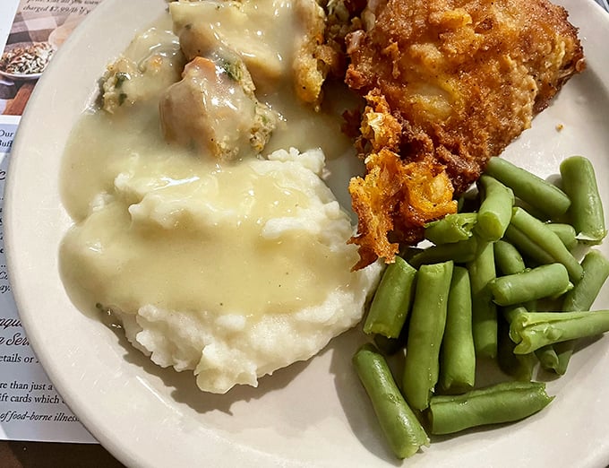 This plate tells the whole story—golden fried chicken, cloud-like mashed potatoes swimming in gravy, and green beans that haven't forgotten their garden roots.