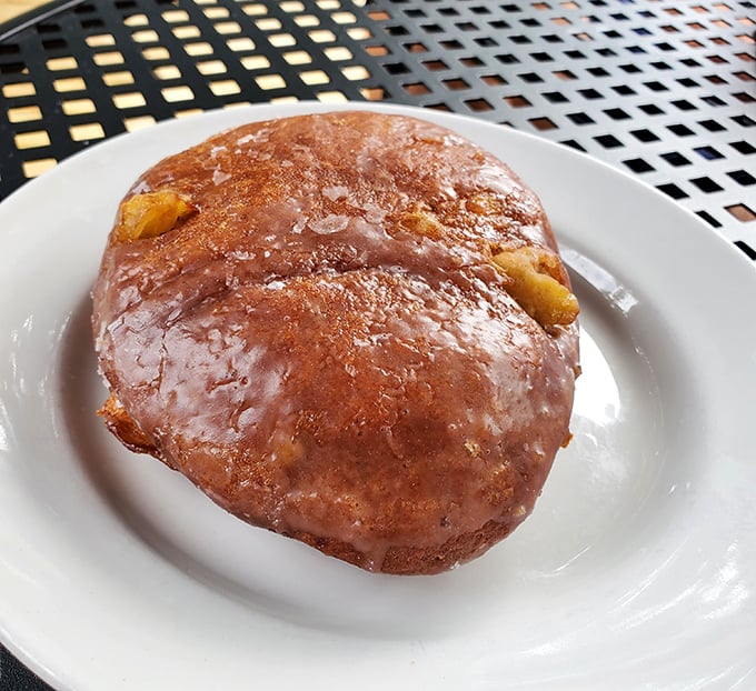 This apple fritter isn't just a donut—it's a glistening monument to morning indulgence, with chunks of apple hiding like buried treasure beneath that crackling glaze. 