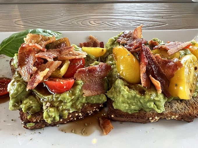 Avocado toast that would make millennials weep with joy—crispy bacon, vibrant tomatoes, and that perfect green spread on artisanal bread.