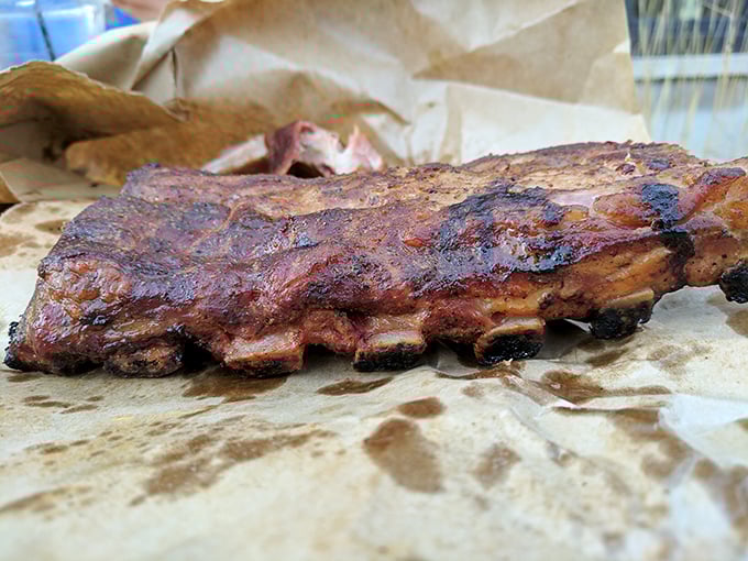 Barbecue architecture at its finest – these ribs showcase that perfect pink smoke ring beneath a bark that deserves its own fan club.