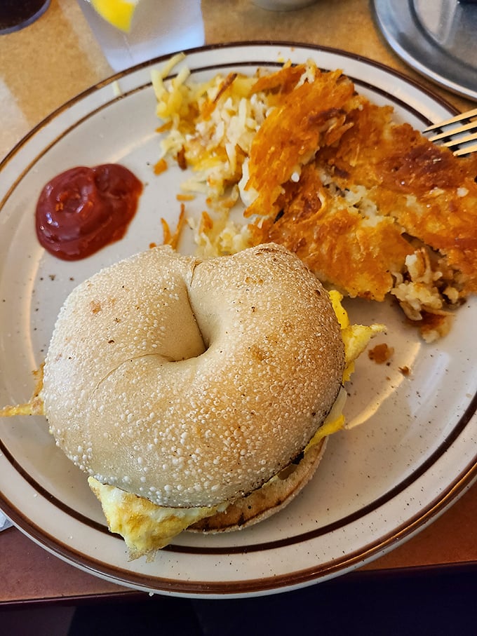 Breakfast sandwich architecture at its finest – the structural integrity of that bagel deserves an engineering award, while the hash browns bring the crispy comfort.
