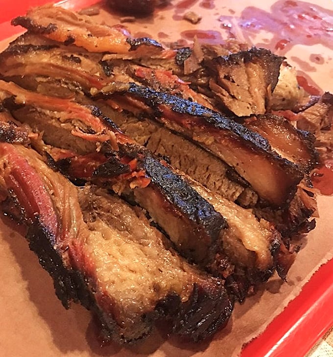 Sliced brisket with that telltale pink smoke ring and glistening bark—this isn't just meat, it's a diploma from Barbecue University.