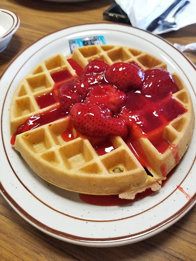 A Belgian waffle drowning in strawberry syrup – the kind of sweet disaster your doctor warned you about.