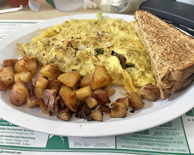 Breakfast architecture at its finest—a golden omelet surrounded by home fries that look like they've been tanned to perfection on a New Hampshire beach.