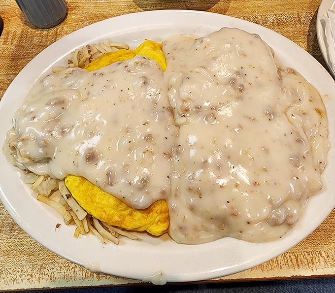 Biscuits smothered in creamy sausage gravy—a dish so comforting it should come with a pillow. Those hash browns underneath are the foundation this masterpiece deserves.