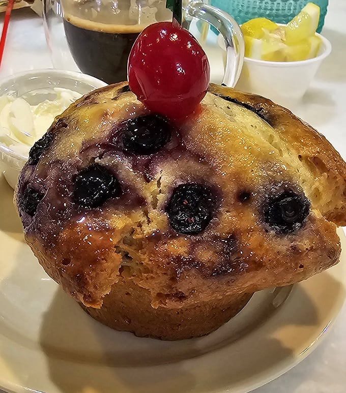 This blueberry muffin topped with a cherry isn't just baked goods—it's edible architecture with fruit jewels that would make any pastry chef proud.
