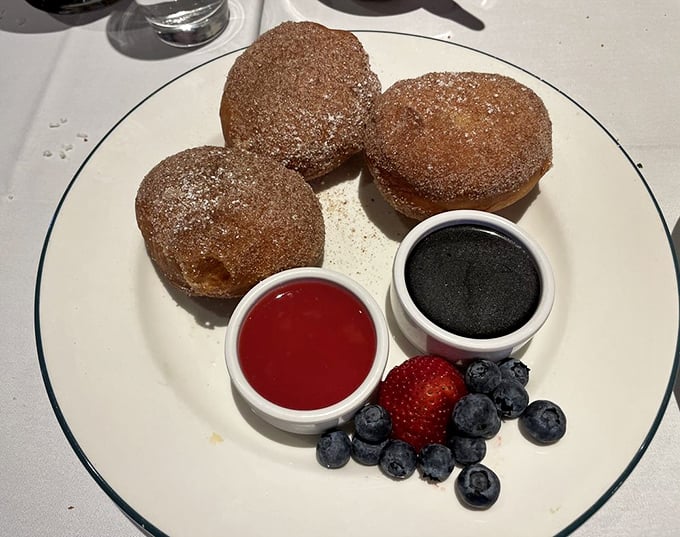 These bombolini aren't just donuts—they're sugar-dusted spheres of happiness served with dipping sauces and berries for good measure.