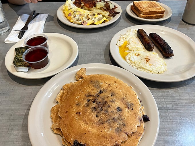 Breakfast symphony: golden pancakes, perfectly fried eggs, and sausages that snap with each bite. Morning glory on pristine white plates.