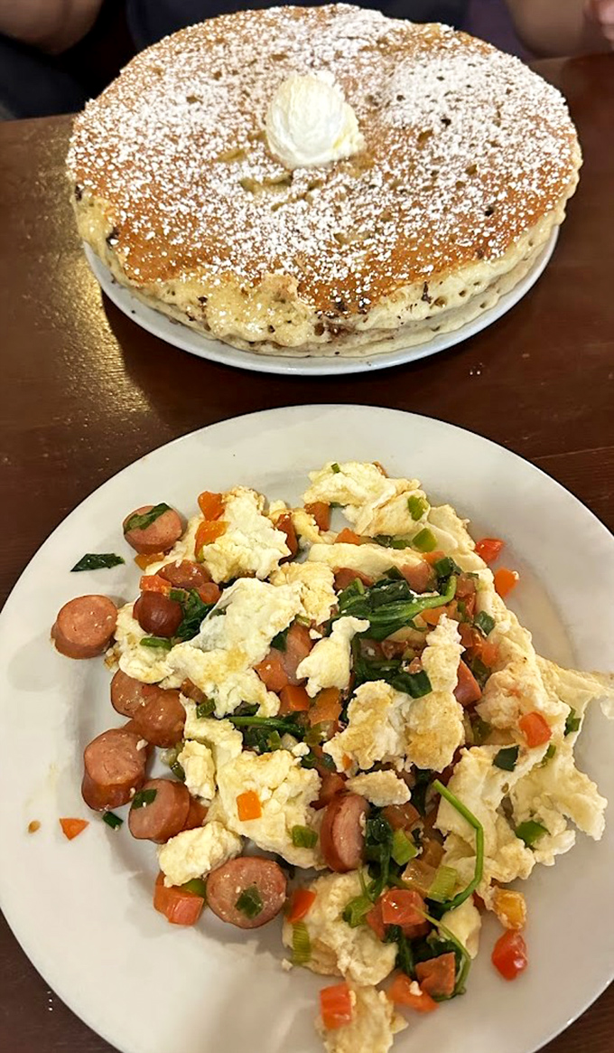 Breakfast alchemy at its finest—fluffy pancakes that could double as a pillow, paired with eggs that bring savory balance to sweet excess.