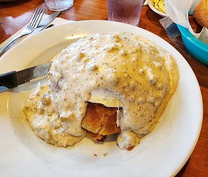 Breakfast goes formal with this gravy-blanketed masterpiece—like your favorite breakfast sandwich decided to dress up for the opera.