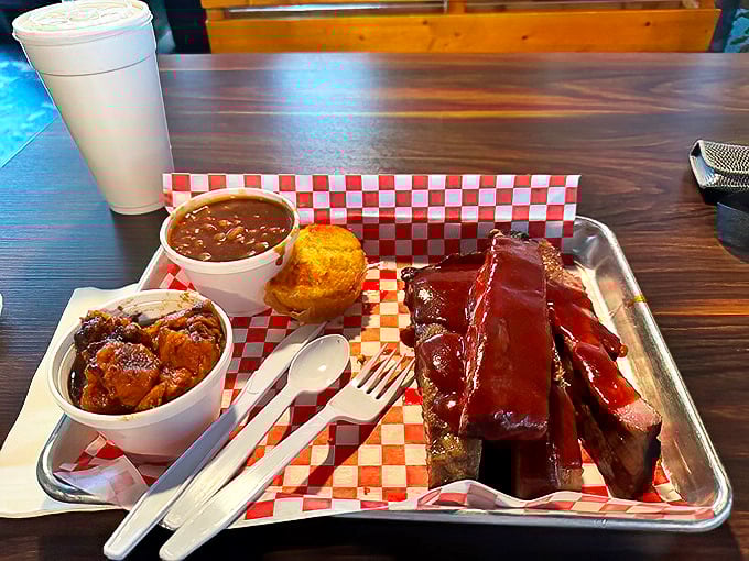 Ribs, beans, and cornbread served on a metal tray with checkered paper—the universal signal that you're about to experience something authentically delicious.