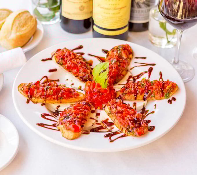 Bruschetta arranged like a sunburst—each crisp toast topped with a mountain of fresh tomatoes and basil, drizzled with balsamic reduction.