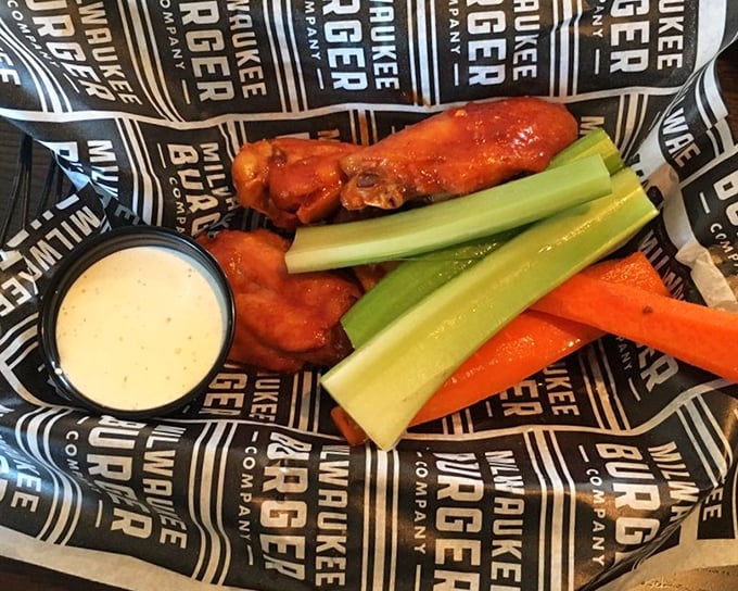 Buffalo wings served with the traditional celery stalks—nature's edible napkins. The sauce clings to each wing like it's afraid of missing the party.
