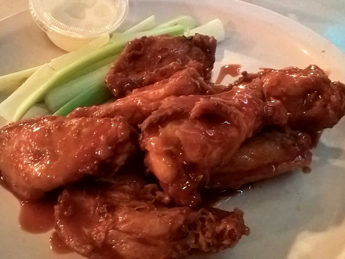 Buffalo wings that don't mess around—crispy, saucy, and unapologetically messy, with celery sticks offering the illusion of healthful balance.