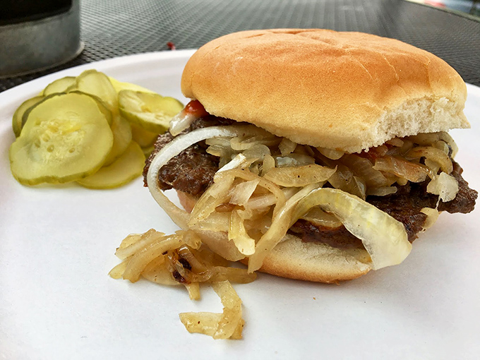Caramelized onions cascade down this burger like delicious lava. The pickle slices aren't garnish—they're essential supporting actors in this flavor play.