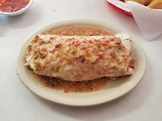 The burrito arrives like a gift-wrapped package of comfort, its flour tortilla barely containing the savory treasures within, glistening with house-made sauce.