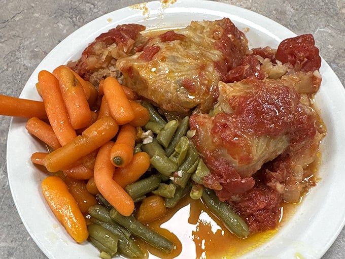 Grandma-approved cabbage rolls swimming in savory sauce alongside perfectly cooked vegetables—the kind of plate that makes you want to hug the chef.