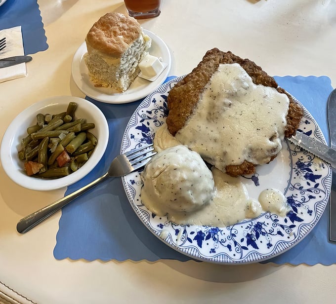 Country-fried steak smothered in peppery gravy with a side of green beans—proof that happiness can indeed be served on a blue-rimmed plate.