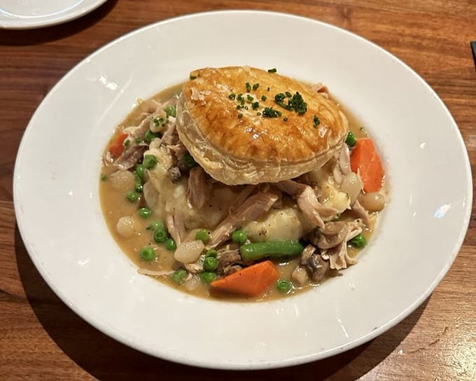 Beneath that golden pastry dome lies chicken pot pie nirvana—a steaming treasure chest of tender meat and vegetables swimming in velvety gravy.
