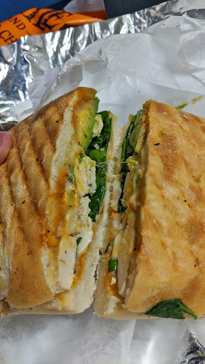 The chicken sandwich reveals its secrets when sliced—a perfect marriage of crispy exterior, juicy interior, and fresh greens that would make any lunch hour memorable.