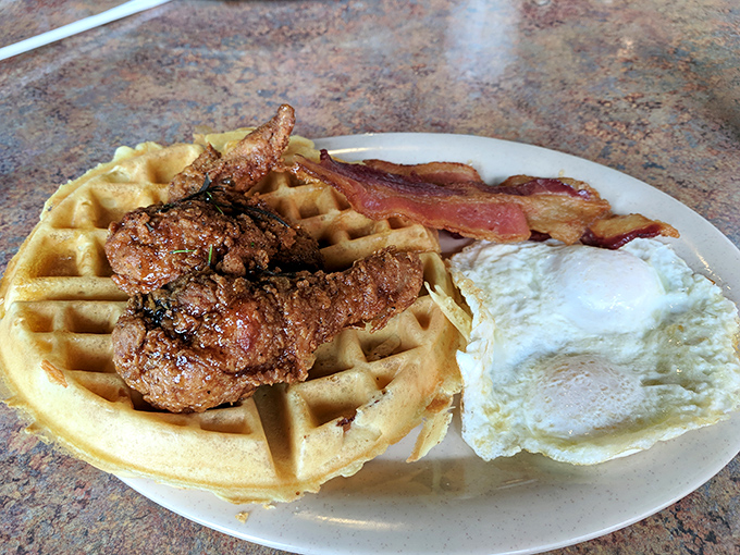 The breakfast holy trinity: golden waffle, crispy fried chicken, and perfectly cooked eggs. Name a more iconic trio—I'll wait.